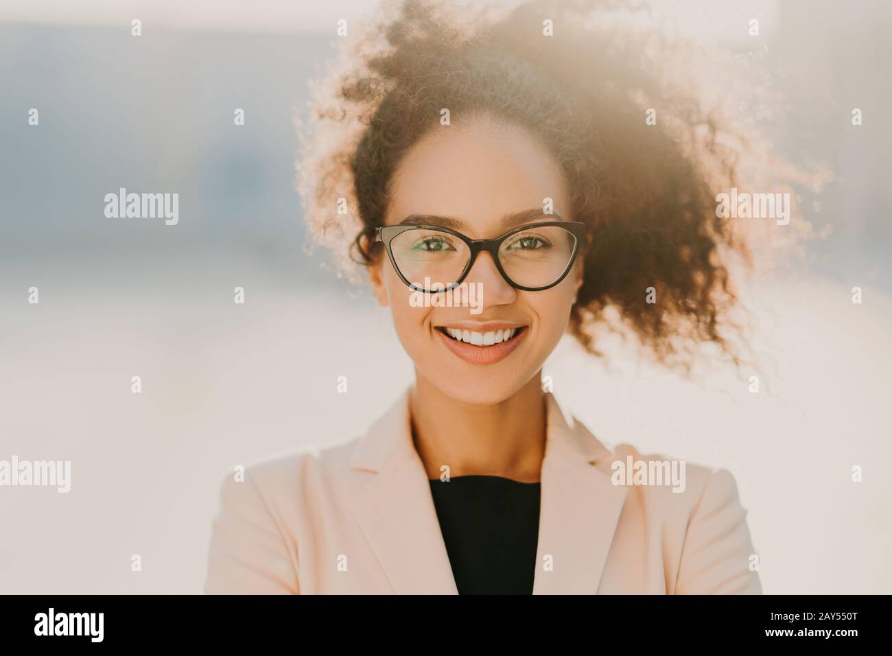 Headshot Of Cheerful Curly Woman With Positive Expression Wears
