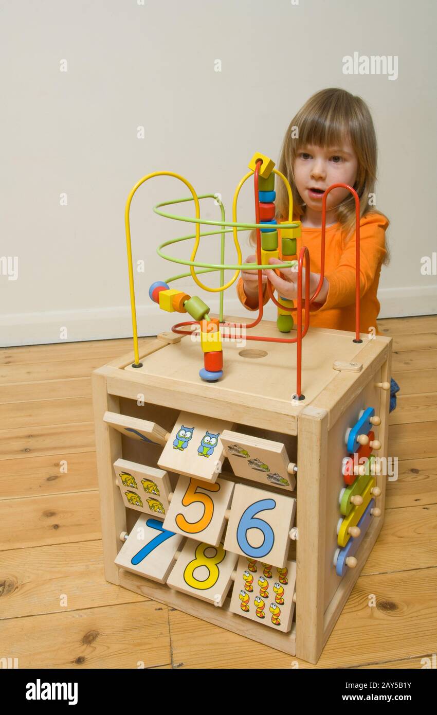 Young girl playing with bead frame activity cube Stock Photo - Alamy
