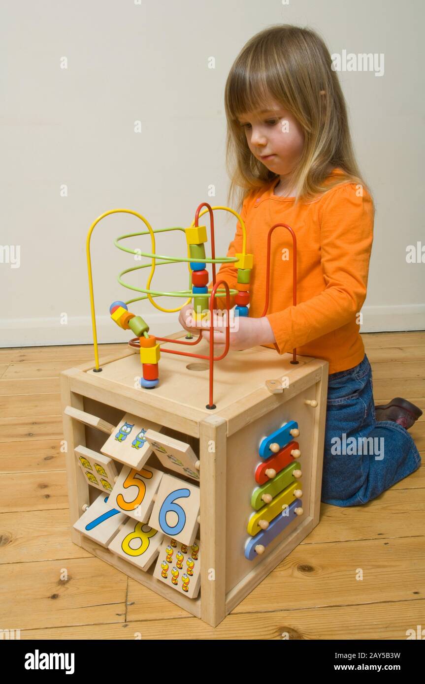 Young girl playing with bead frame activity cube Stock Photo - Alamy