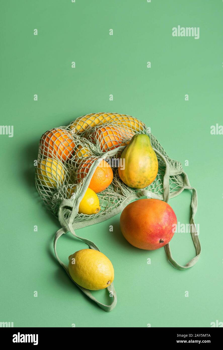 Organic tropical fruits mix in a fabric mesh shopping bag on a green ...