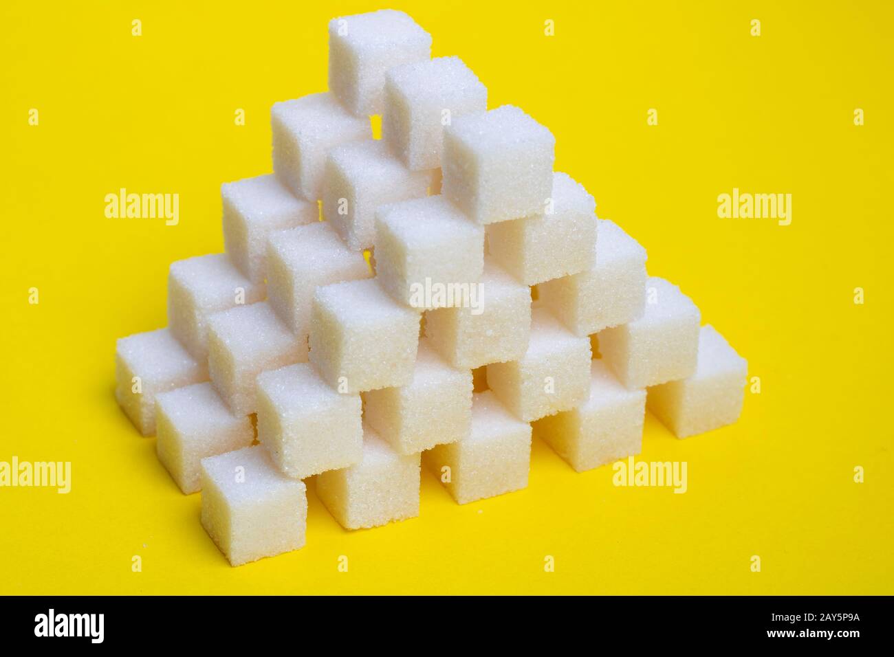 Sugar cubes pyramid on a yellow background, creative food idea Stock ...