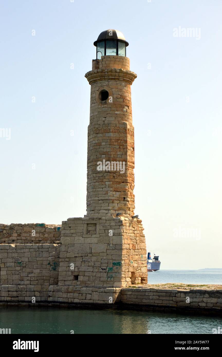 Marine lighthouse in a port of Crete with ramparts and the ocean Stock ...
