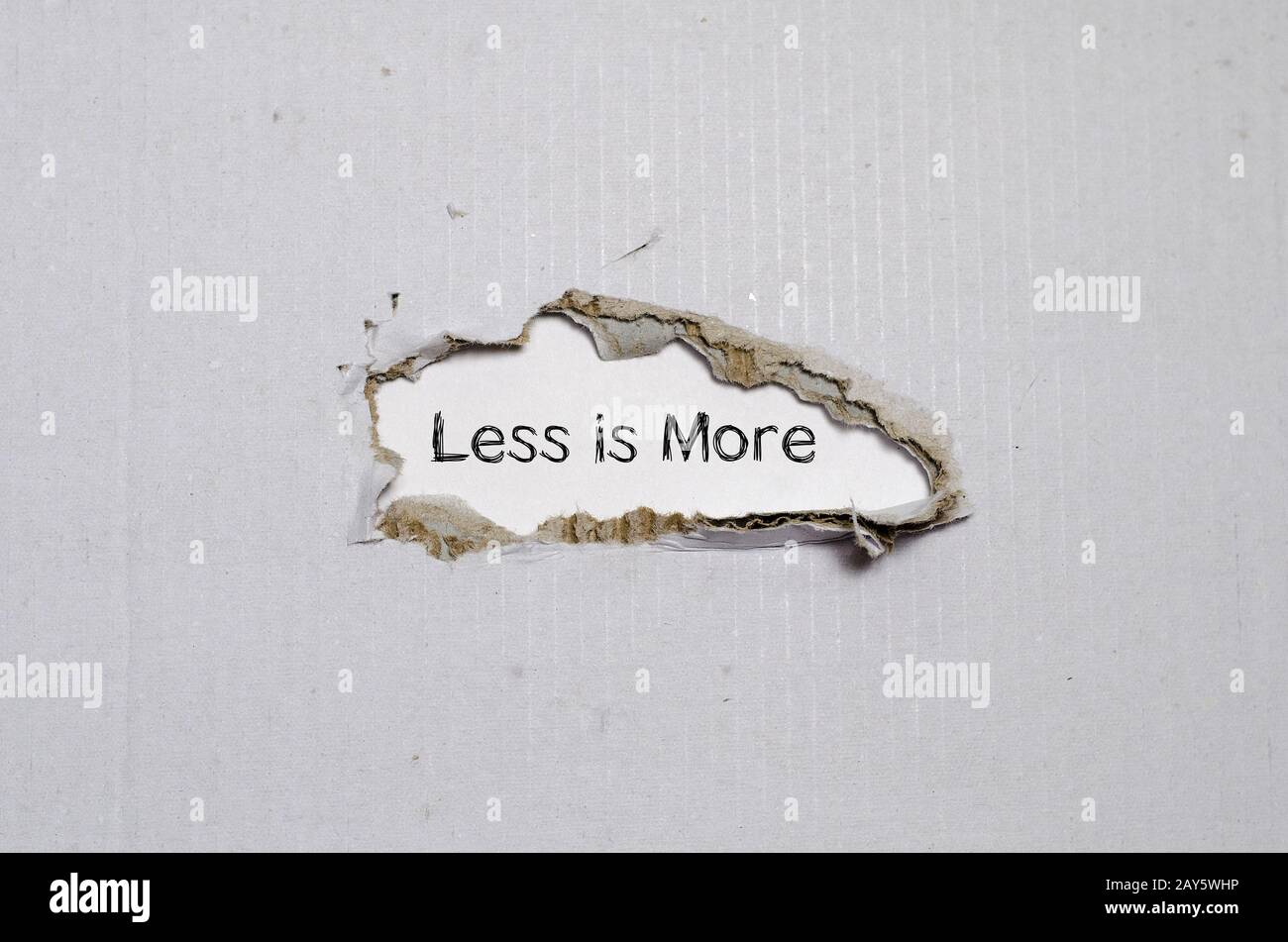 The word less is more appearing behind torn paper Stock Photo - Alamy