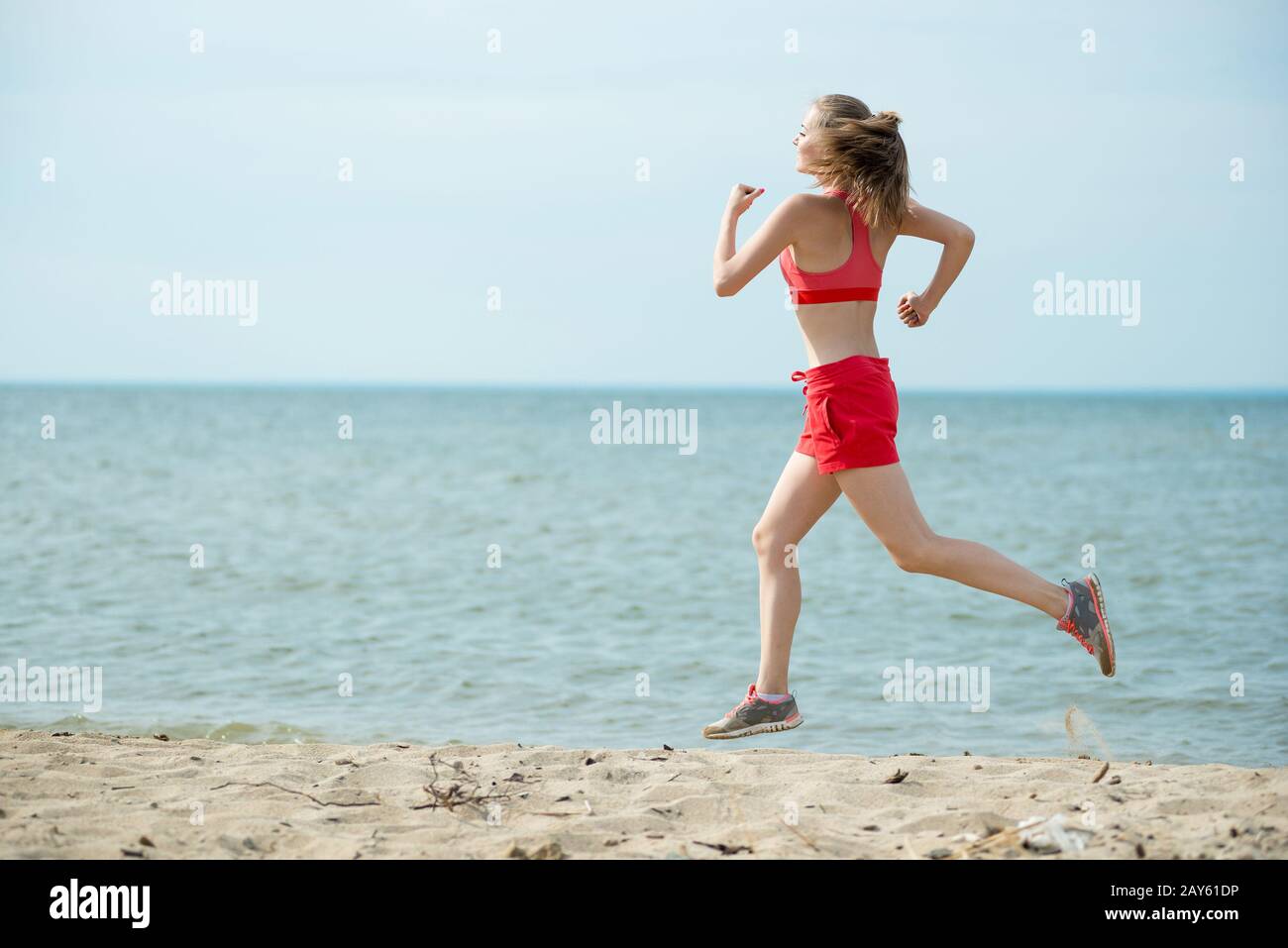 Young lady running at the sunny summer sand beach. Workout. Jog Stock ...