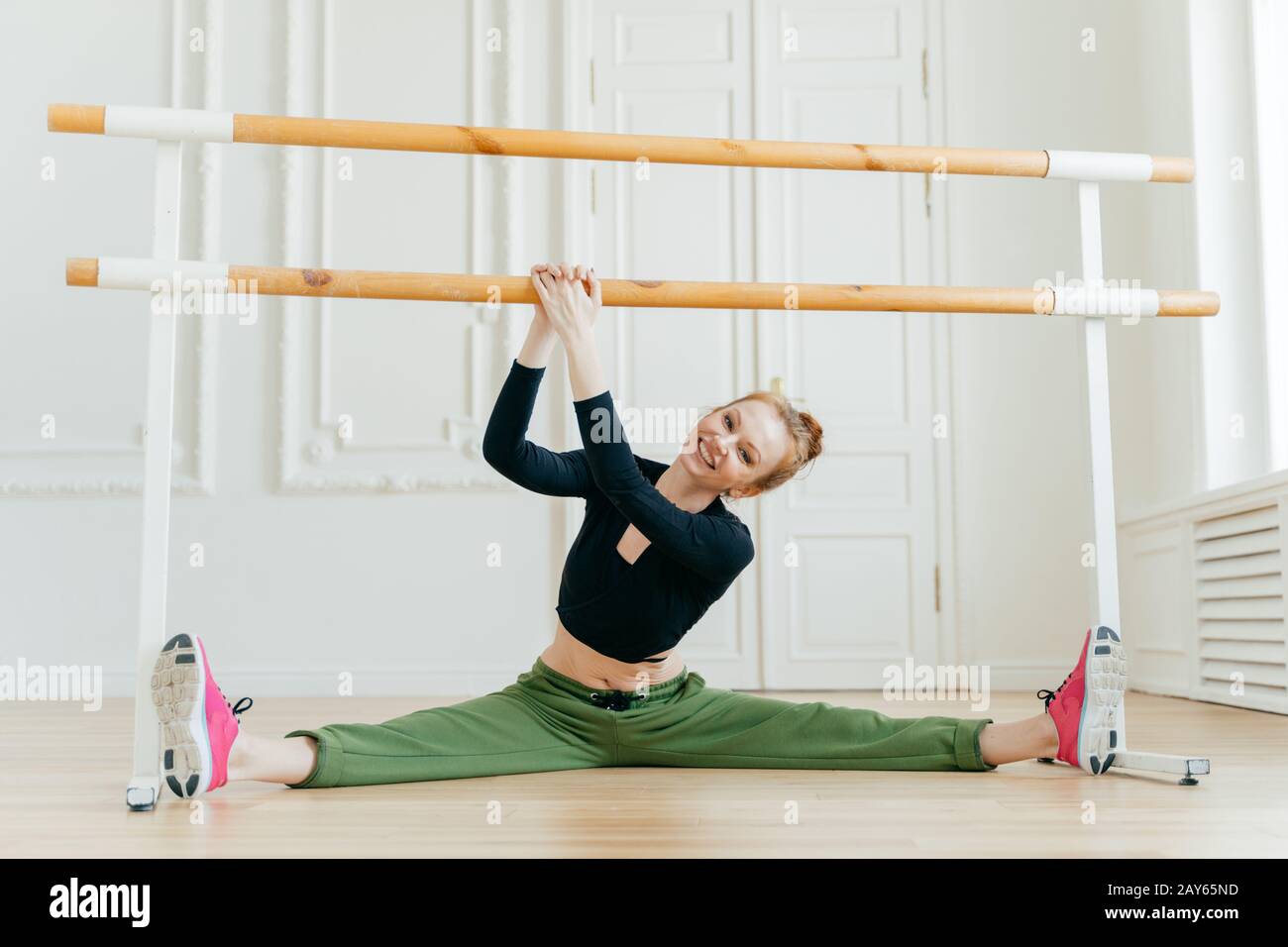 Caucasian female ballerina spreads legs sideways, shows splits, holds ...