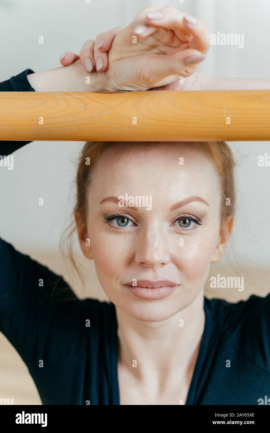Headshot of talented skilled female ballet dancer poses near barre, has ...