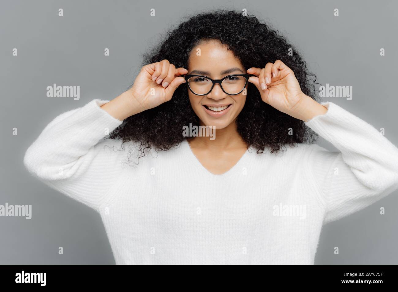 Smiling optimistic curly female with pleased facial expression, keeps ...