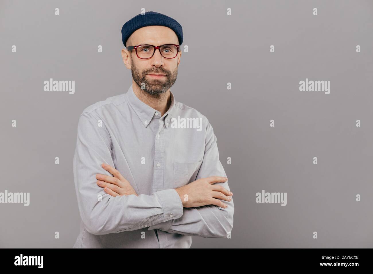 Photo of serious male keeps arms folded over chest, dressed in white ...