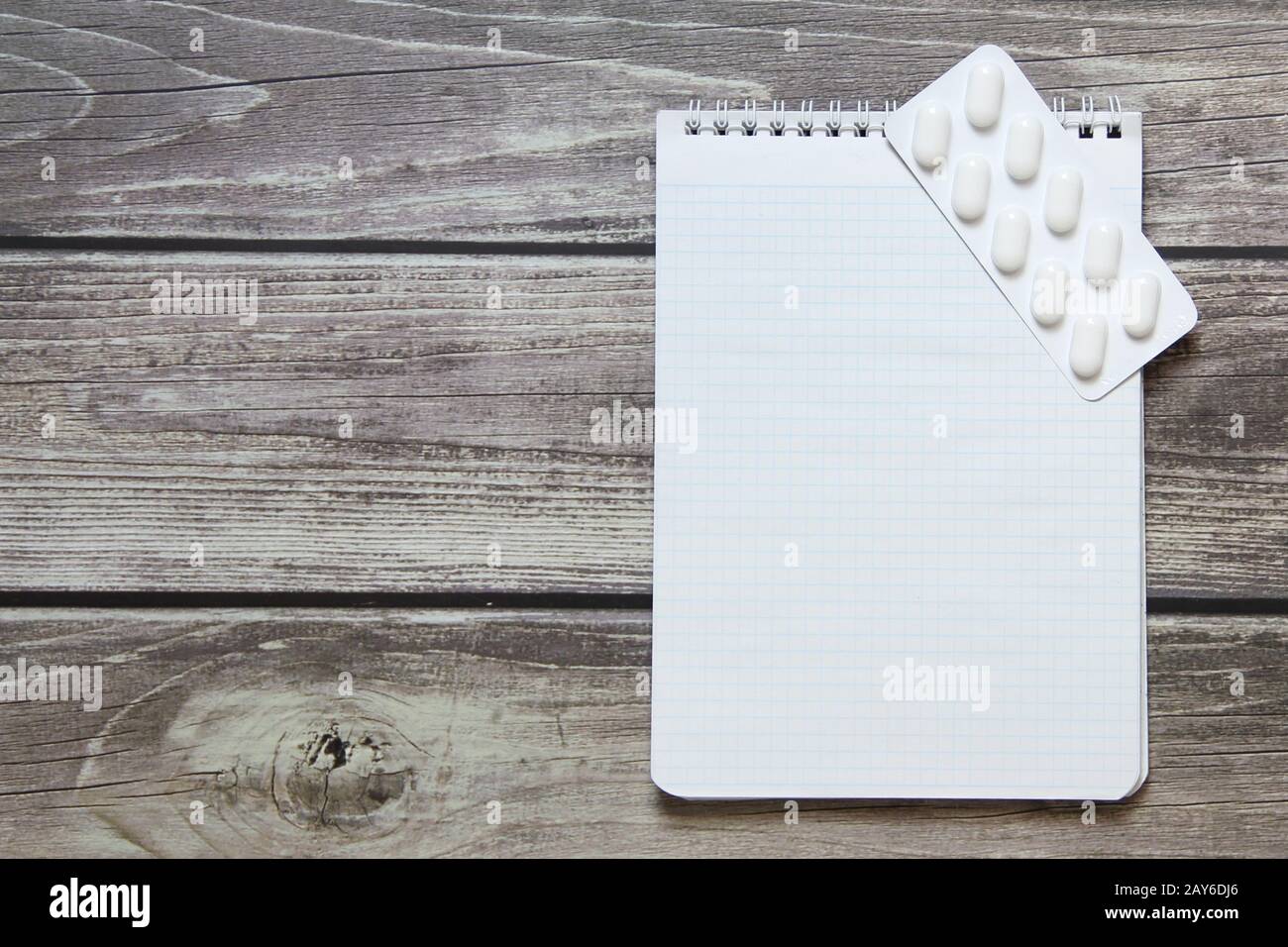Notepad with a blank white sheet in a checker paper with pills in a ...