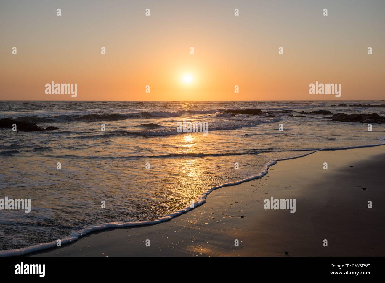 Colorful Namibian sunset with low sun and small waves Stock Photo - Alamy