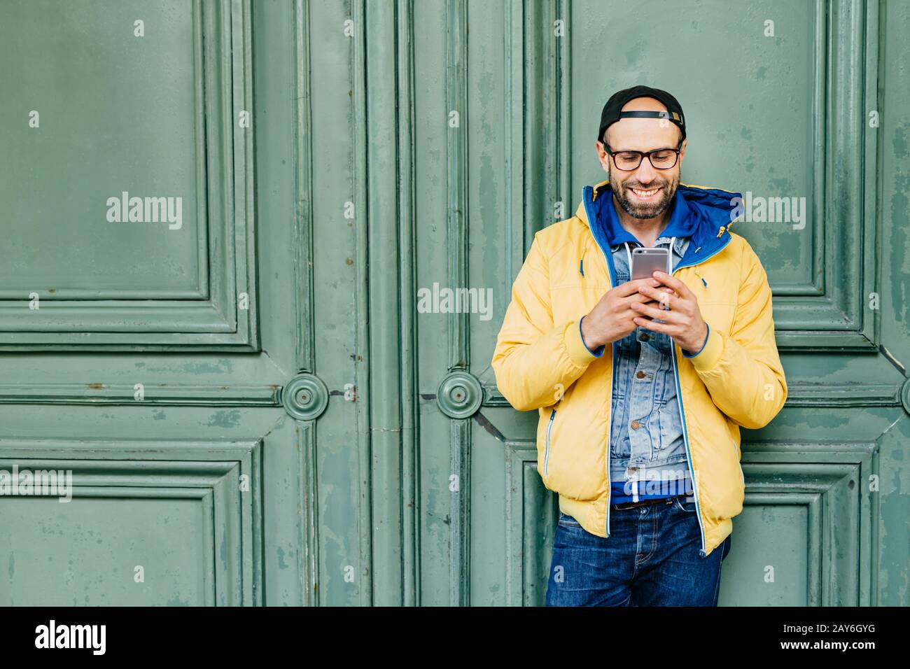 Headshot of stylish man with beard and broad forehead in yellow anorak ...