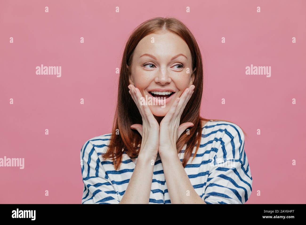 Isolated shot of pretty beautiful woman looks aside, keeps both hands ...