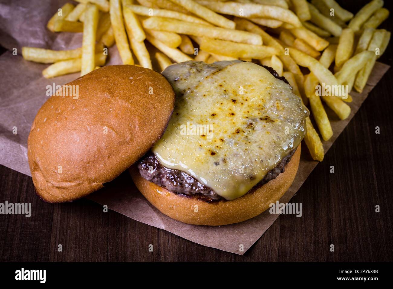 Craft beef burger with cheese and french fries on wood table and rustic ...