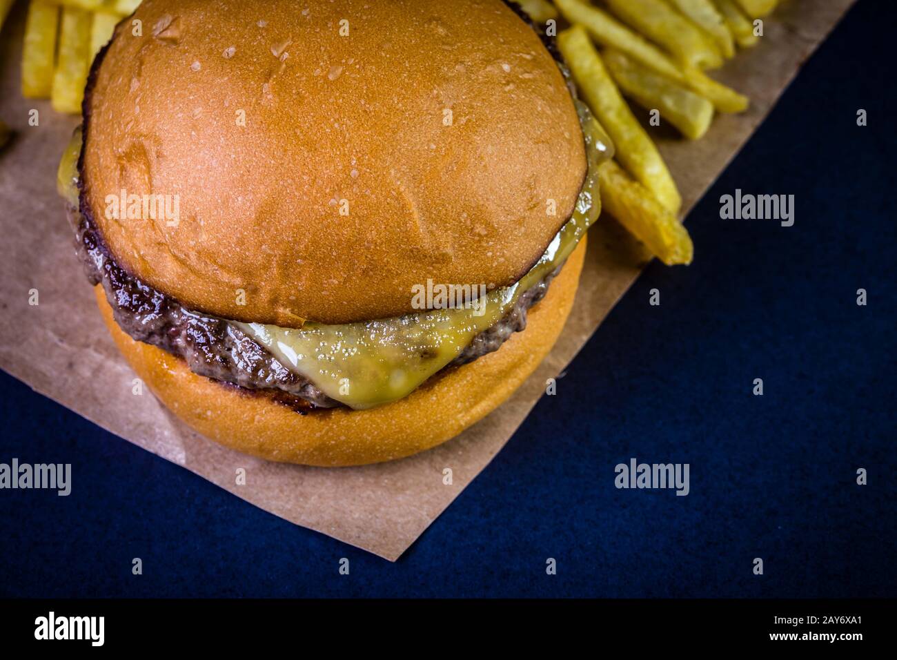 Craft beef burger with cheese and french fries on wood table and rustic ...