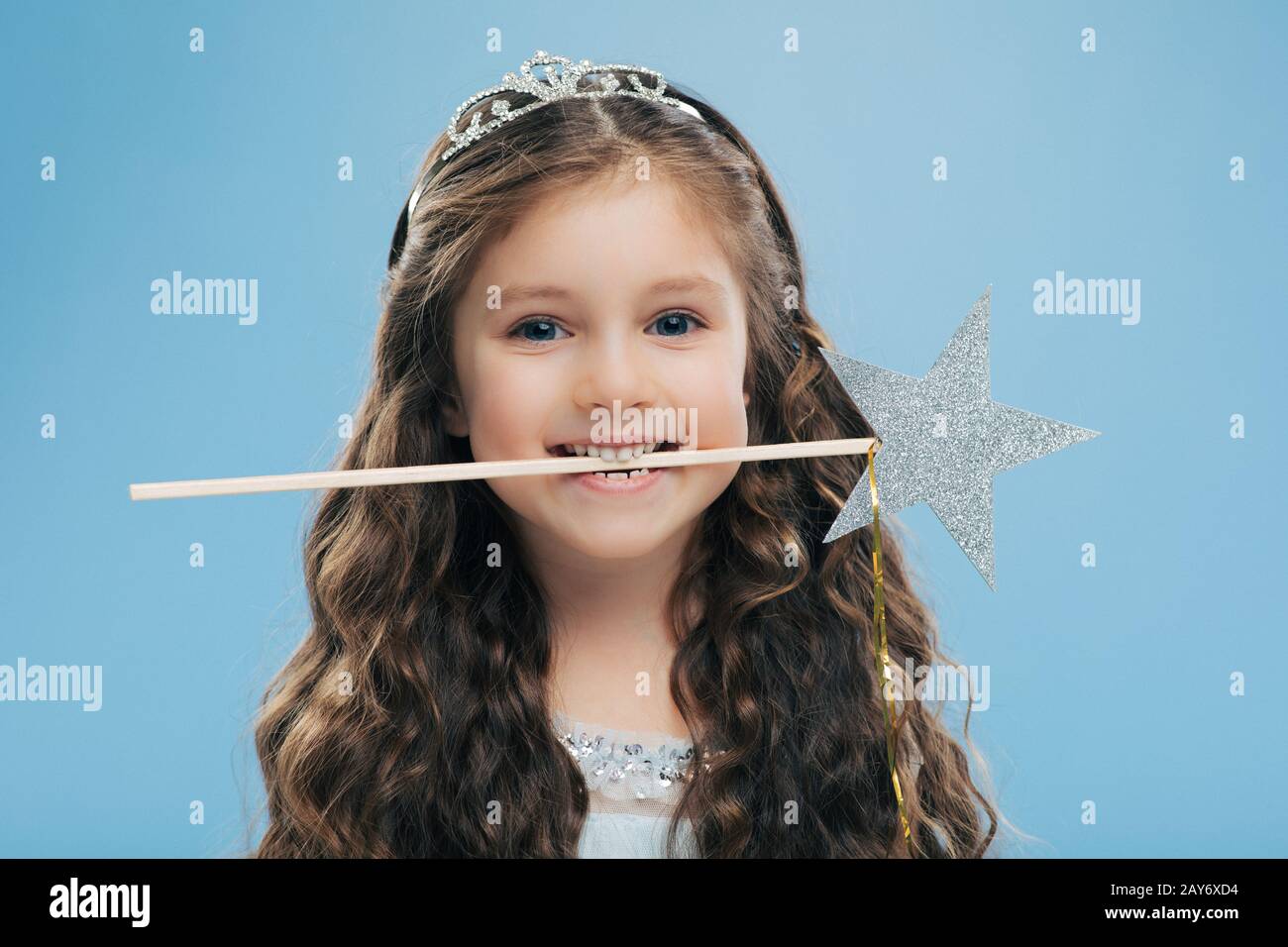 Horizontal shot of attractive smiling small kid holds magic wand in ...