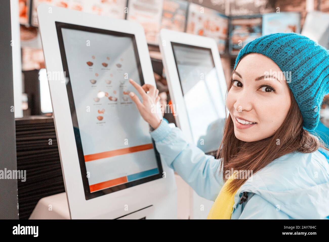A woman orders food in the touch screen terminal with electronic menu ...