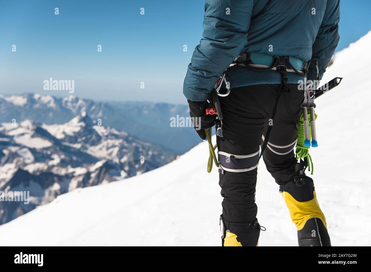 Close up A young guy climber holds in his hand an ice-ax standing on a ...