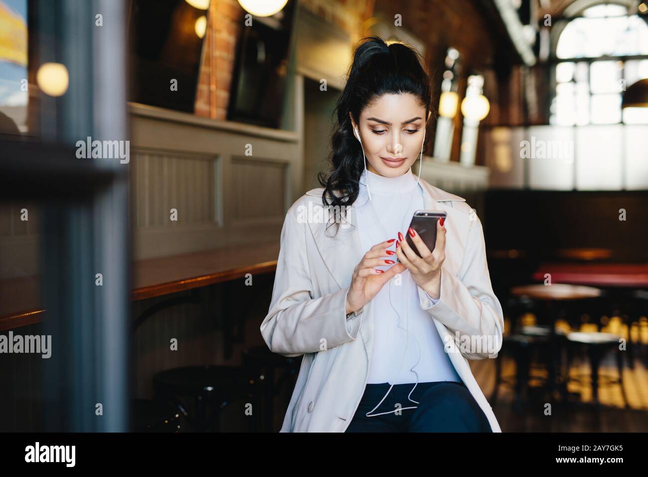 Pretty brunette woman with pony tail and appealing appearance sitting ...