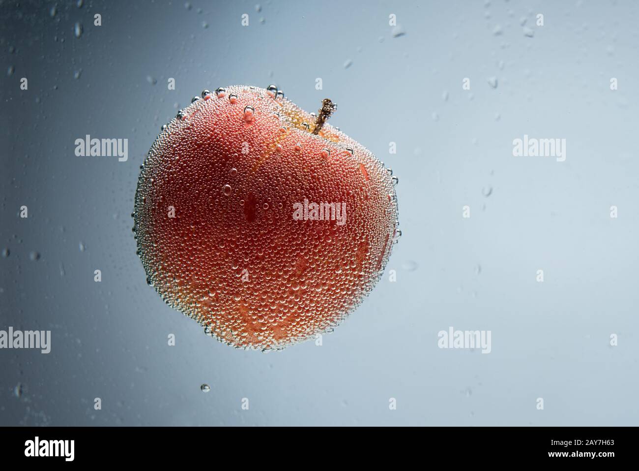Single apple floating in blue water Stock Photo - Alamy