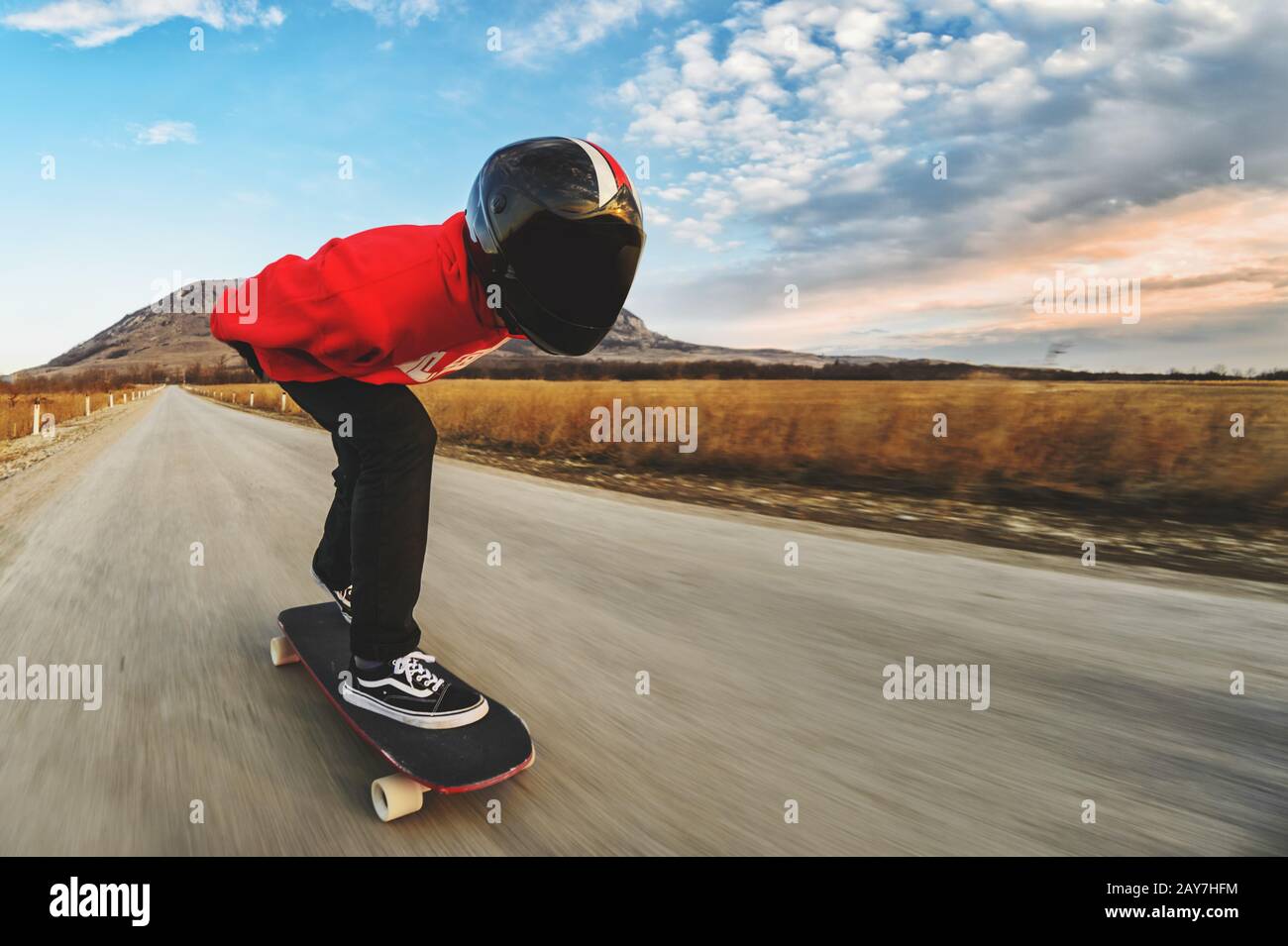 A young man in helmet and a leather suit in a special rack rides a ...