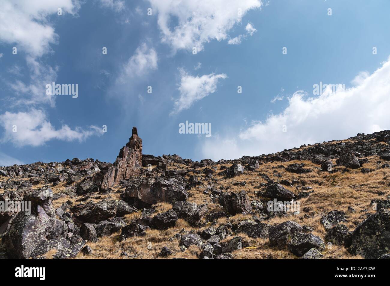 High-mountainous sharp rocks against the blue sky and white clouds ...