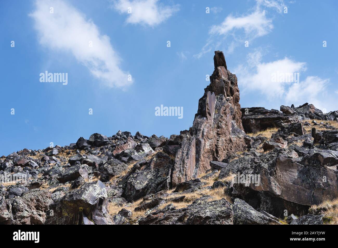 High-mountainous sharp rocks against the blue sky and white clouds ...