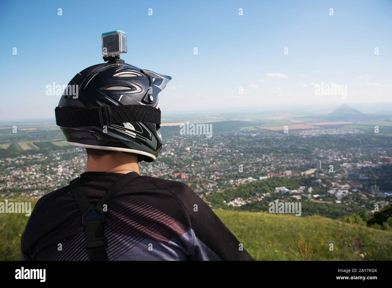View from the back. MTB rider looks from the mountain to the city which ...