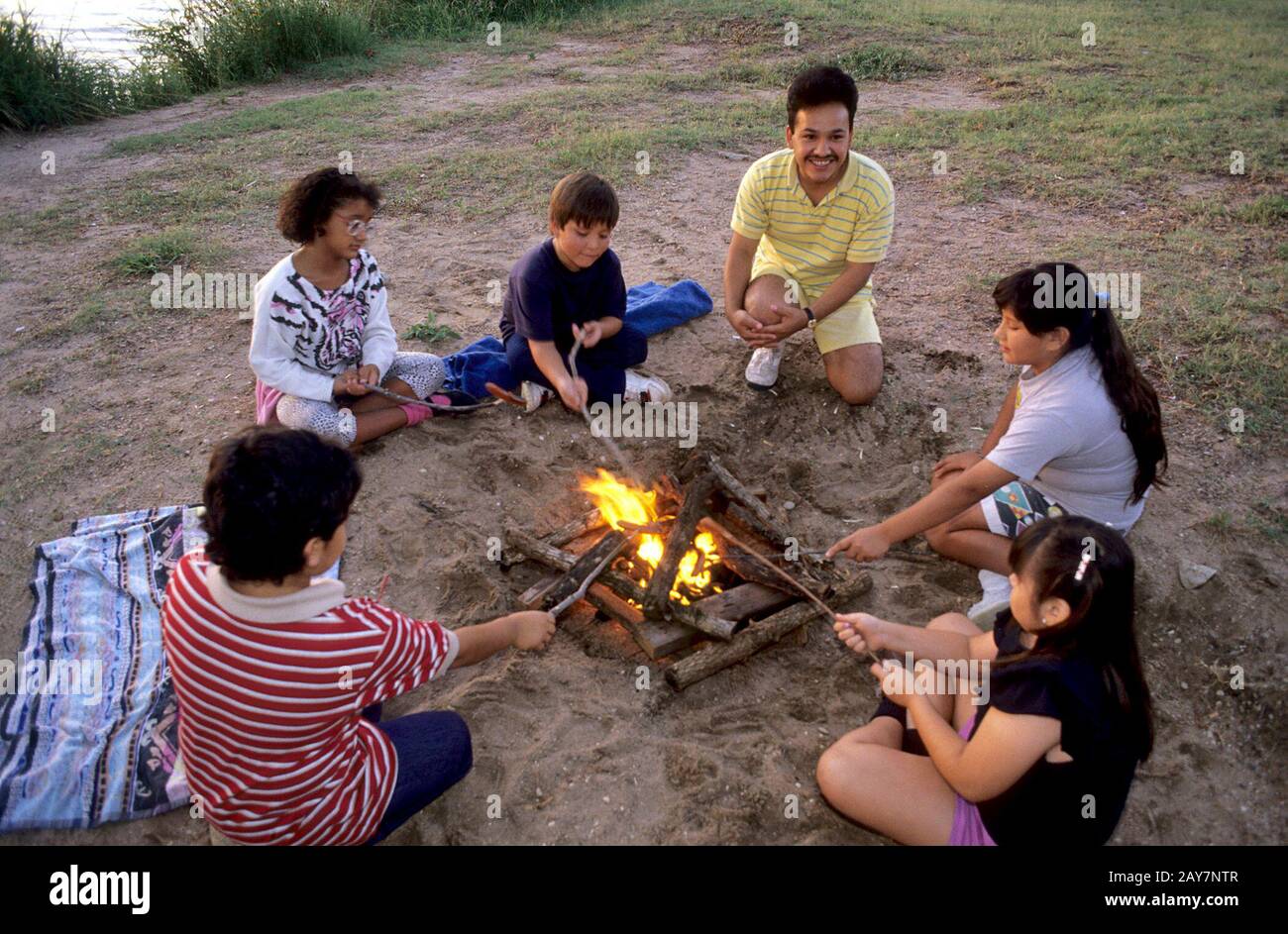 Hispanic children having cookout with adult supervision. ©Bob Daemmrich ...