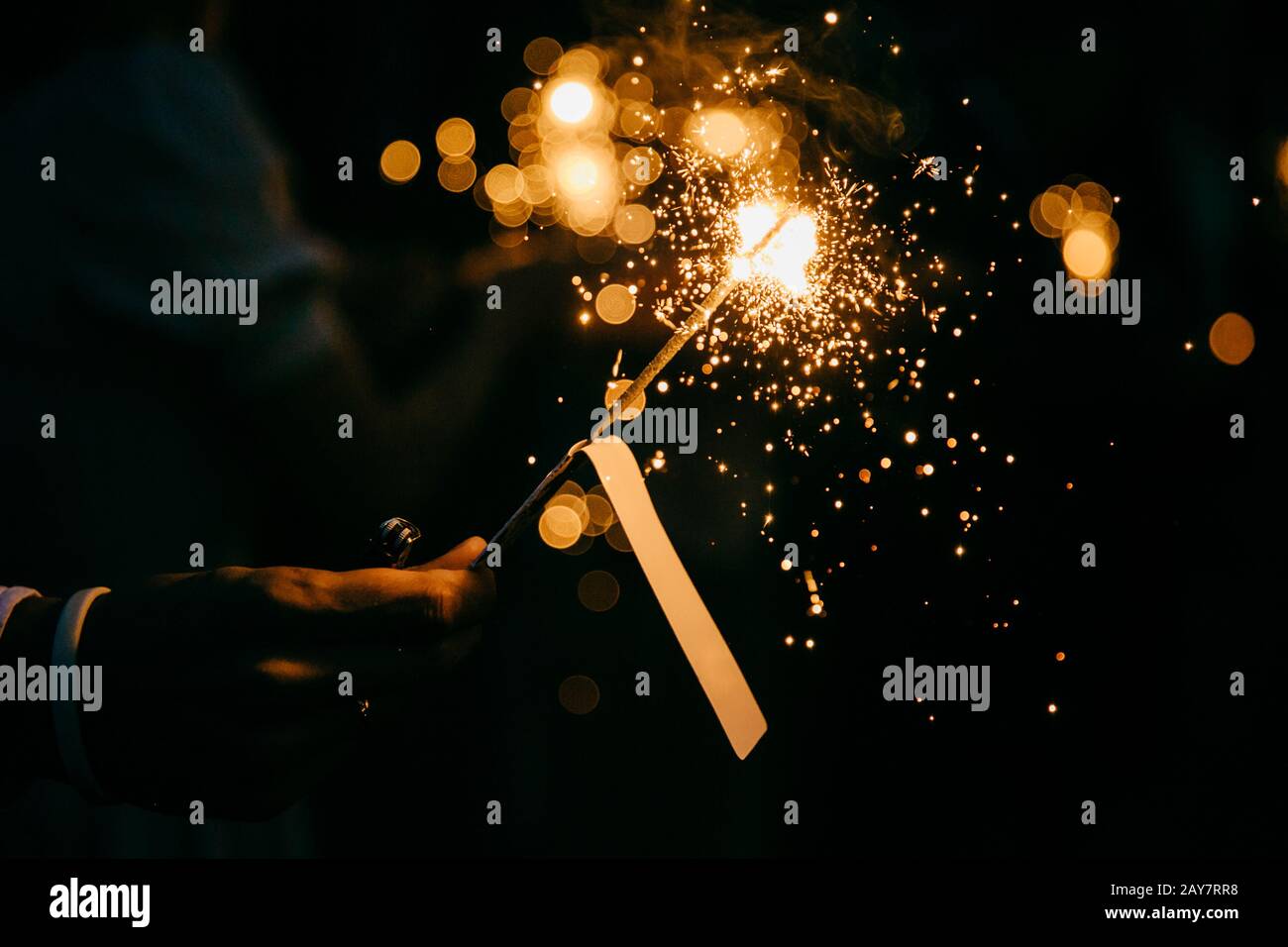 Bright festive sparkler in hand. Burning sparkle in darkness ...