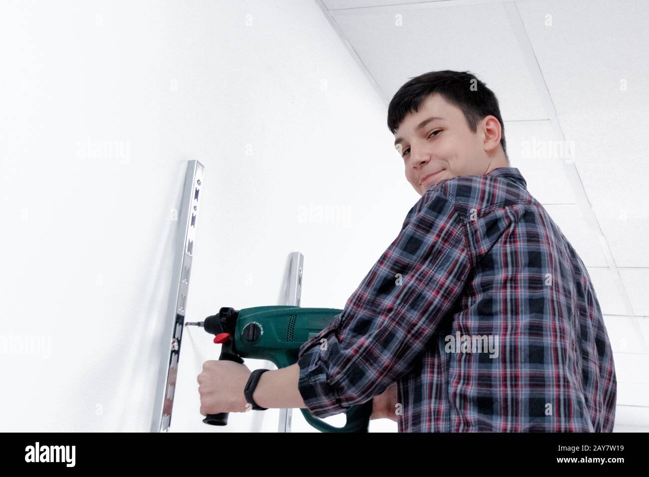 The boy works as a builder, holding a drill or perforator. Concept of ...