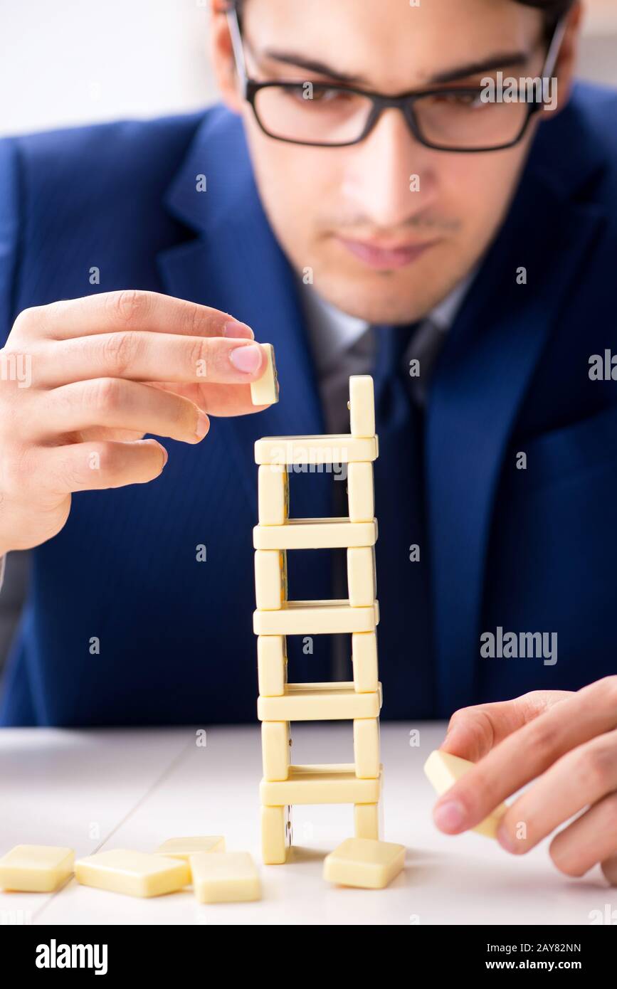 Young businessman building domino tower in office Stock Photo - Alamy