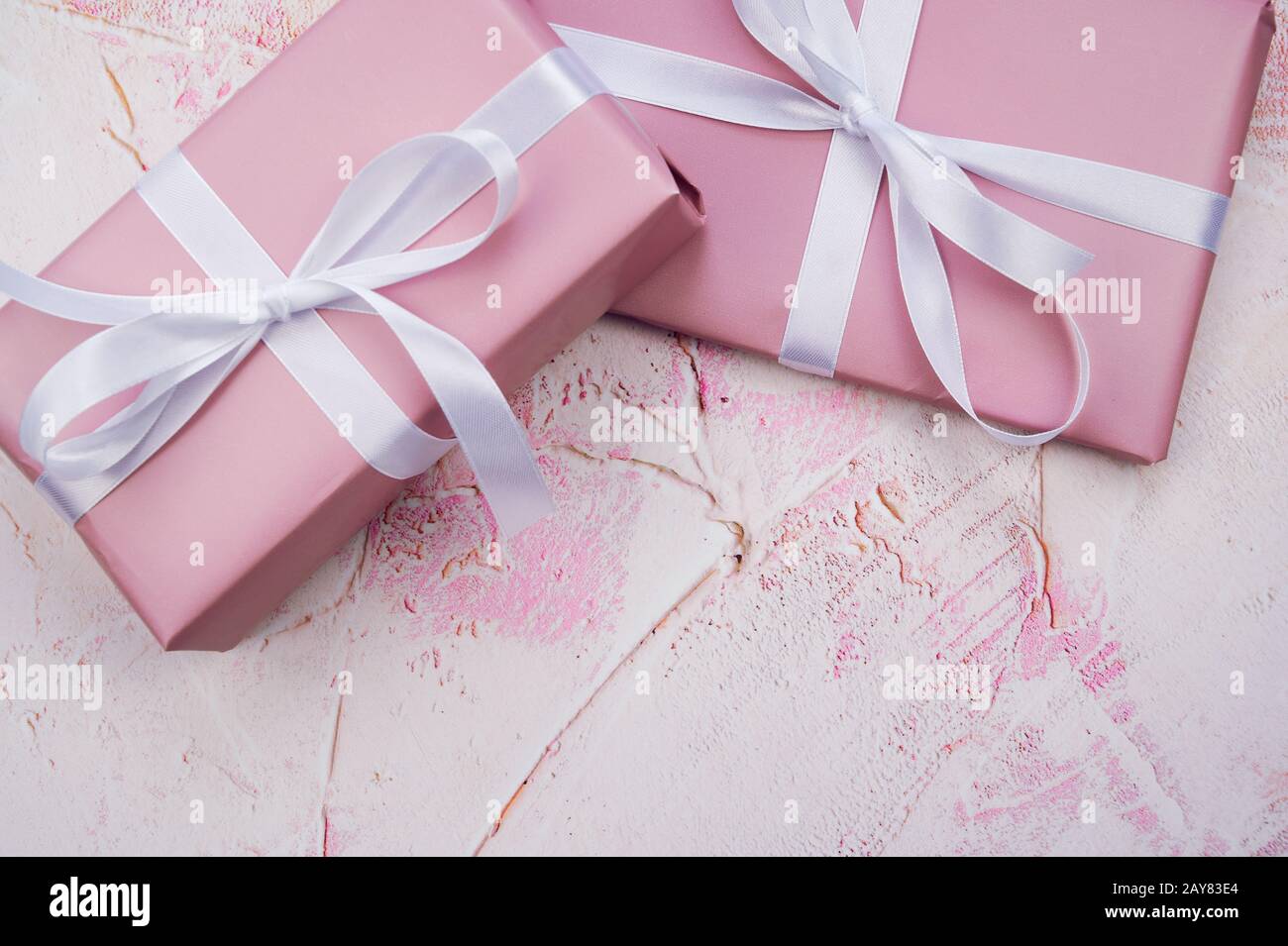 horizontal color photo of two pink presents with a white ribbon against ...