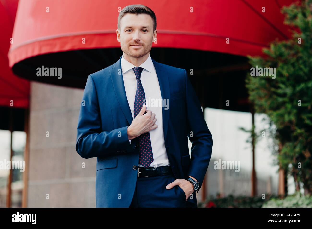 Handsome male company owner dressed formally, stands outside, has ...