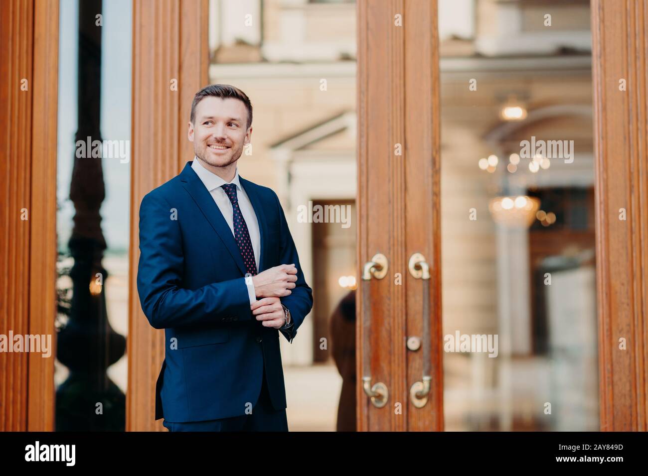 Horizontal shot of handsome successful male executive worker stands ...
