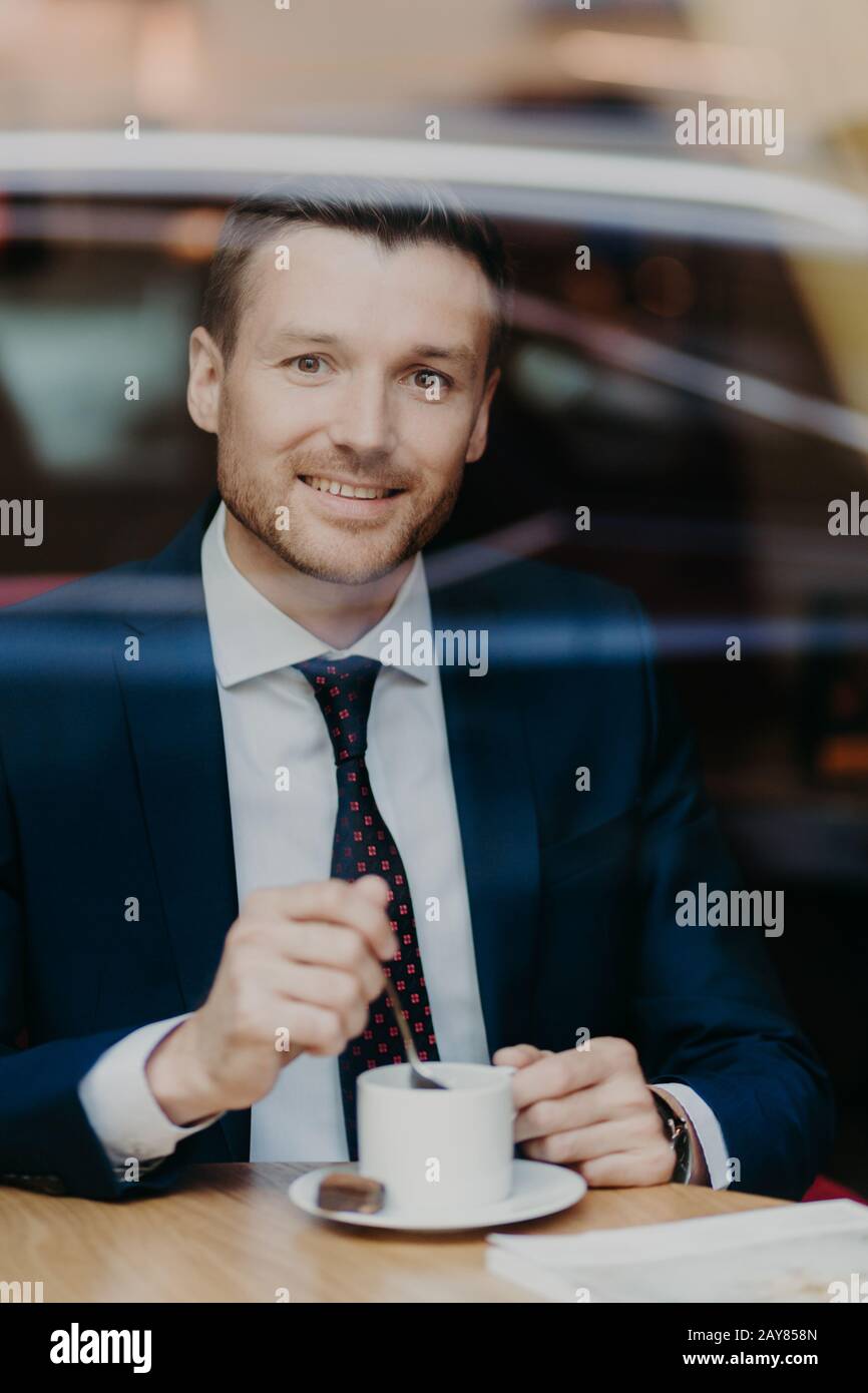 Verrtical shot of delighted handsome male professional worker in black ...