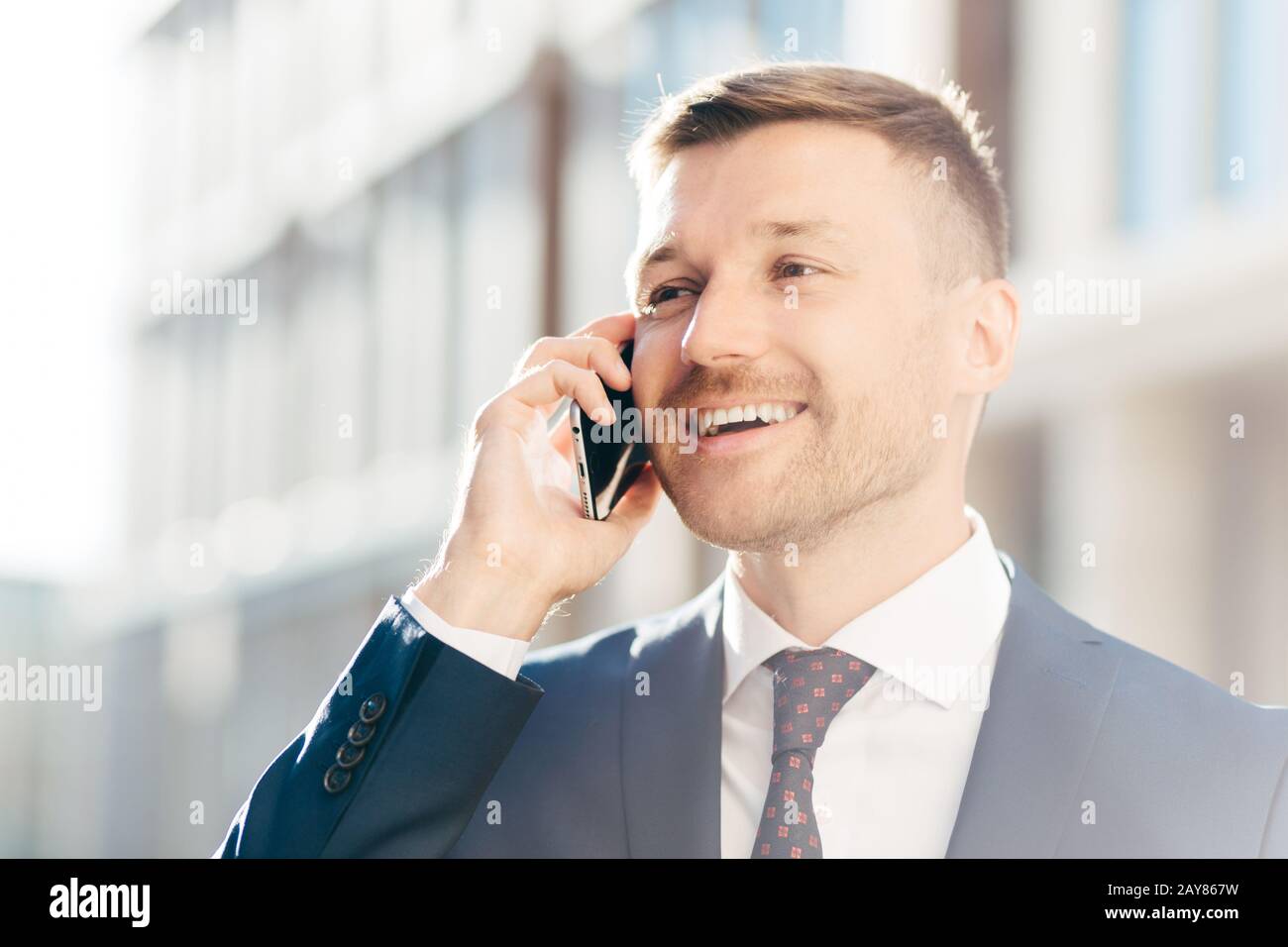 Portrait of successful positive office employee has phone conversation ...