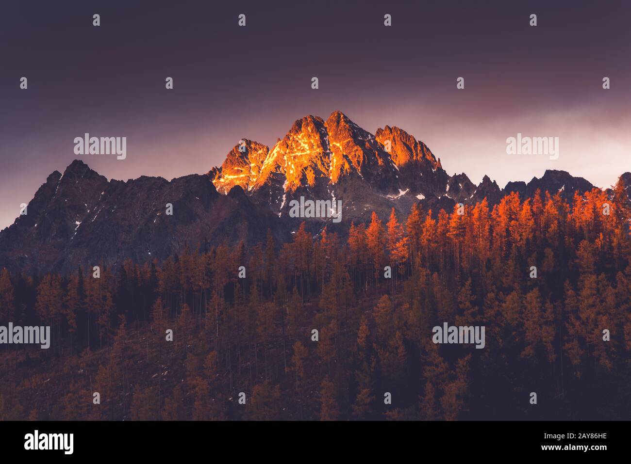 Last sun light hits high mountains peak at sunset Stock Photo - Alamy