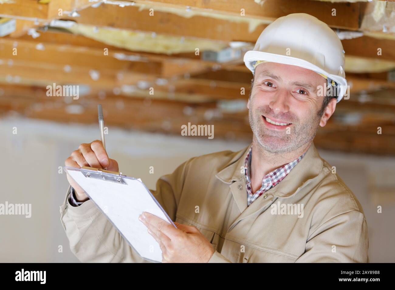 builder in with clipboard over white wall background Stock Photo - Alamy