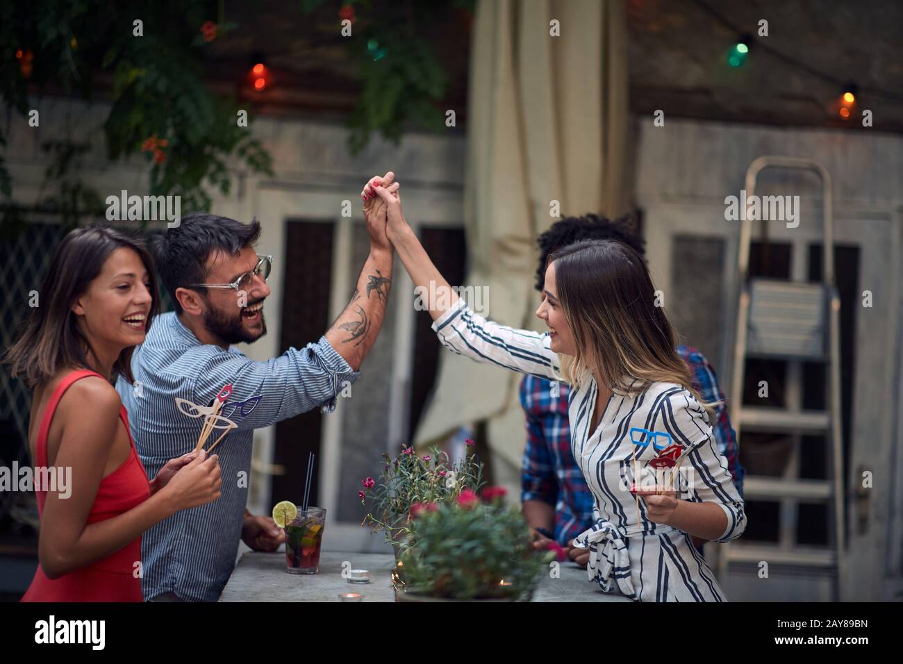 two couples socializing in outdoor cafe, joking, laughing, high five ...