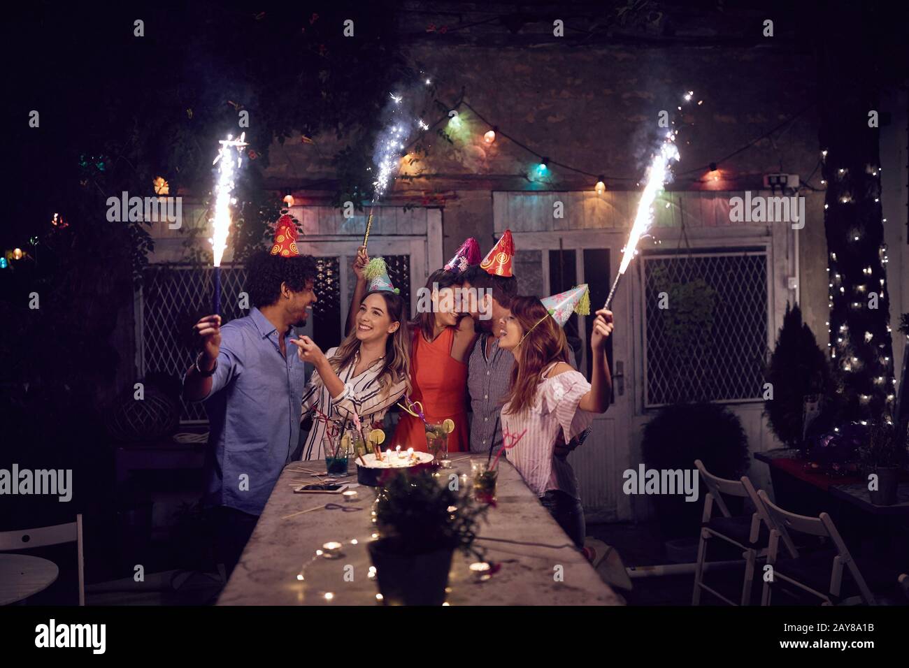 friends at birthday party with handheld fireworks in their hands ...