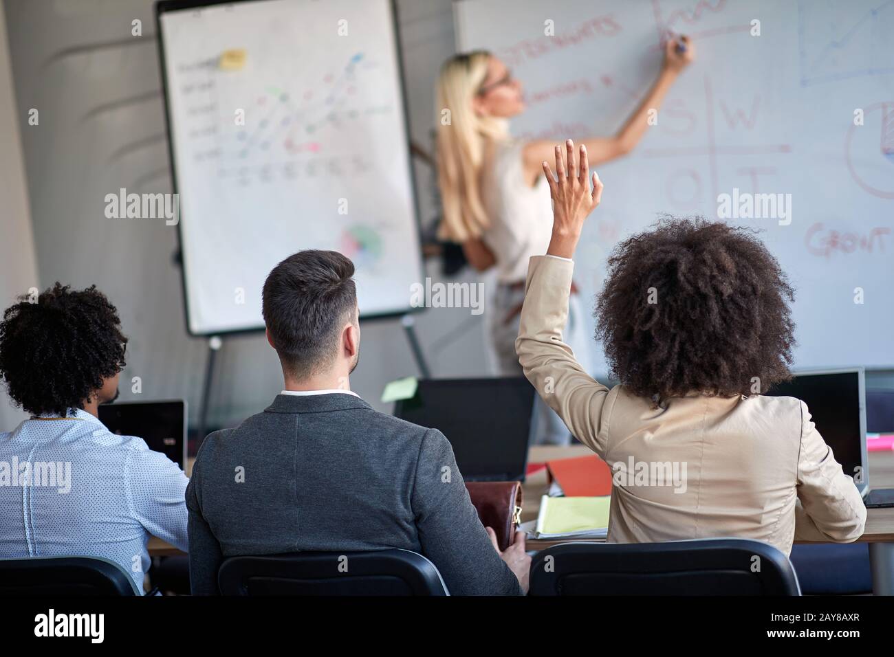 young business female rising hand at the meeting asking permission to ...
