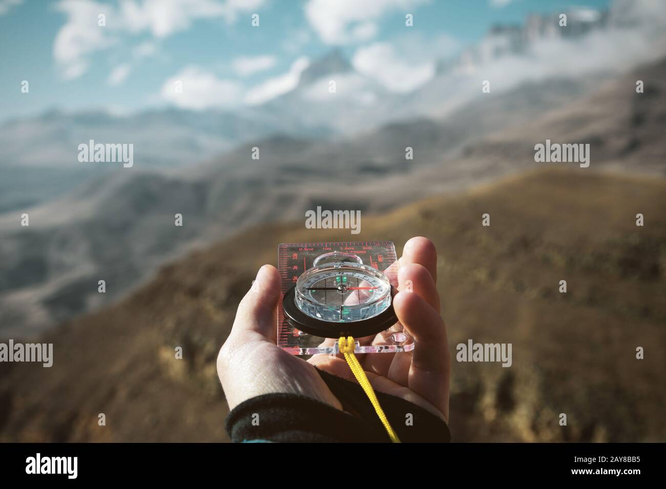 Viewpoint shot. A first-person view of a man's hand holds a compass against the background of an ...