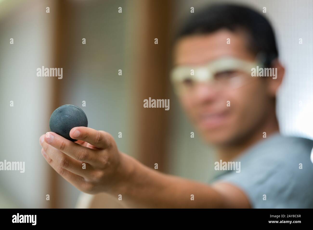 portrait of handsome squash player showing a ball Stock Photo - Alamy