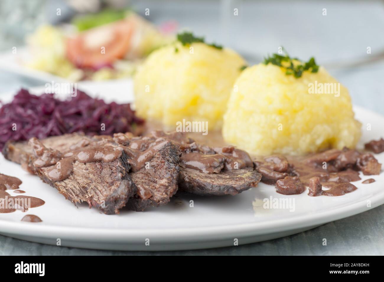 German Sauerbraten with red cabbage on a plate Stock Photo - Alamy