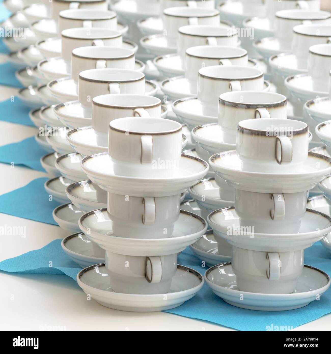 White coffee cups with plates stand stacked in a row Stock Photo - Alamy