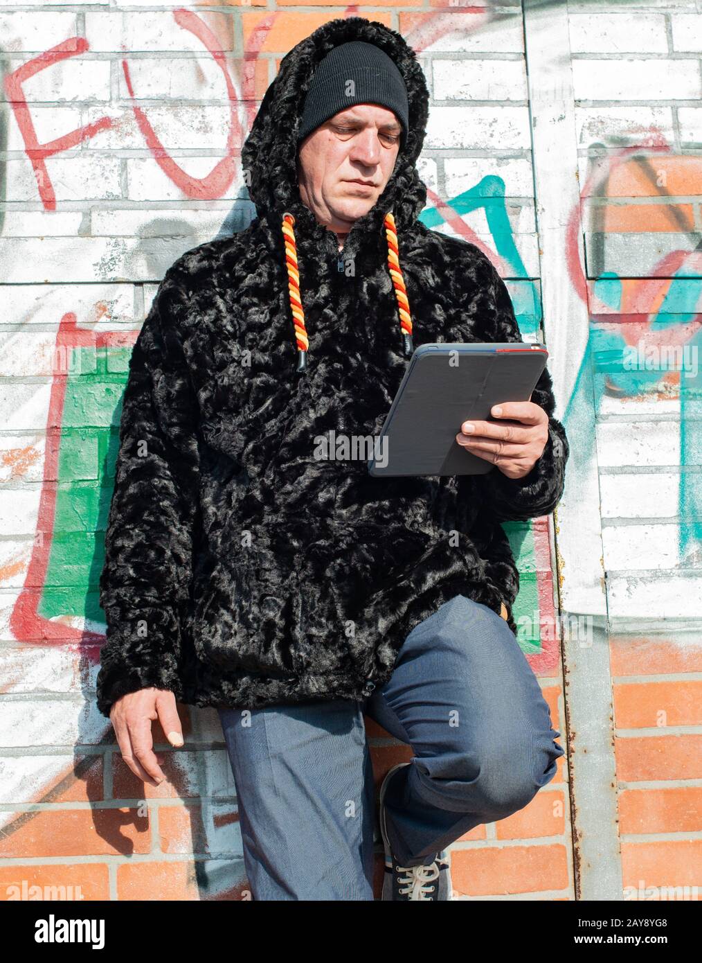 Posing of a Man model in Faux fur jacket in front of a graffiti wall ...