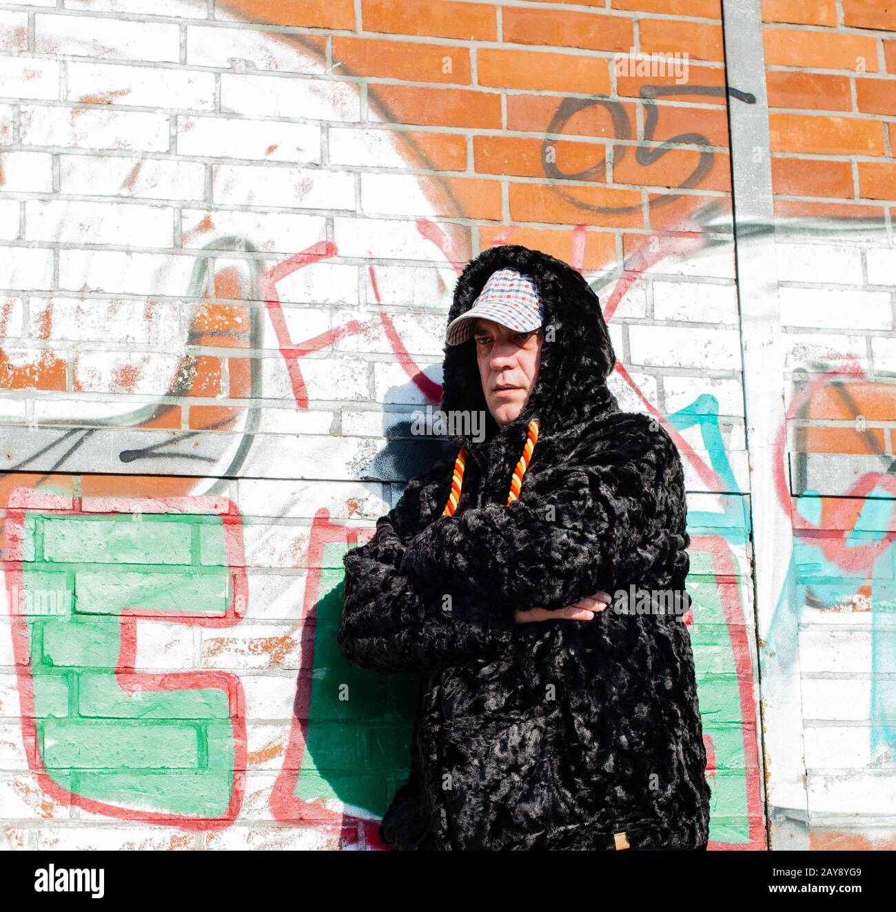 Posing of a Man model in Faux fur jacket in front of a graffiti wall ...