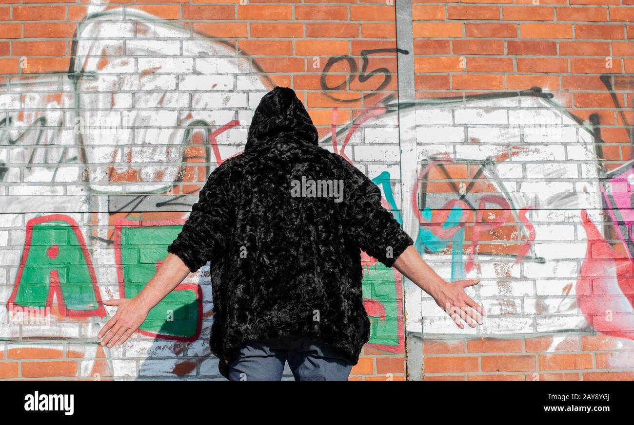 Posing of a Man model in Faux fur jacket in front of a graffiti wall ...