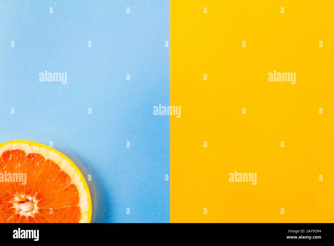 Single grapefruit slice close-up on blue and yellow background Stock ...