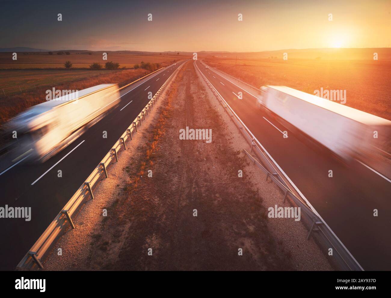 Trucks in the highway, dramatic sunset, motion blur. Cargo ...